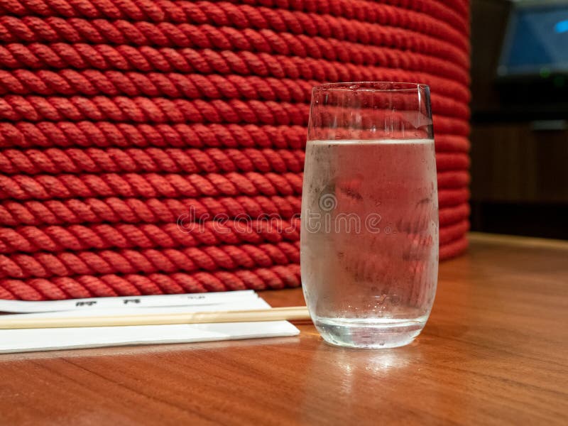 Glass of Water Next To Decorative Column Covered in Red String in Asian ...