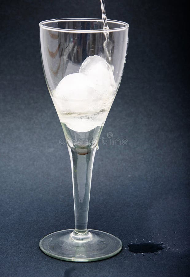 A Glass of White Wine with Pieces, Ice Cubes. Wine with Ice on a Black ...