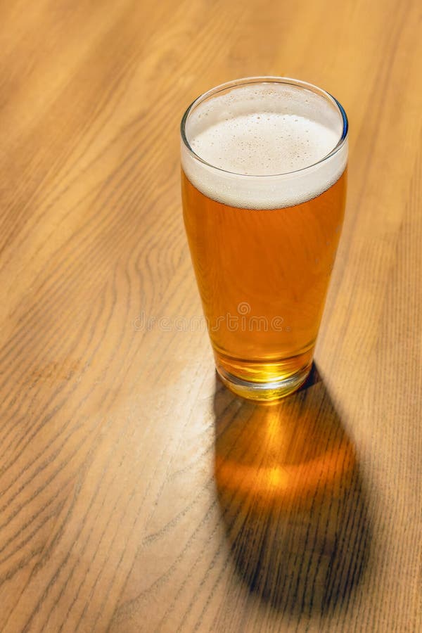 A Glass of Yellow Beer with a Cast Shadow on the Table Stock Photo ...