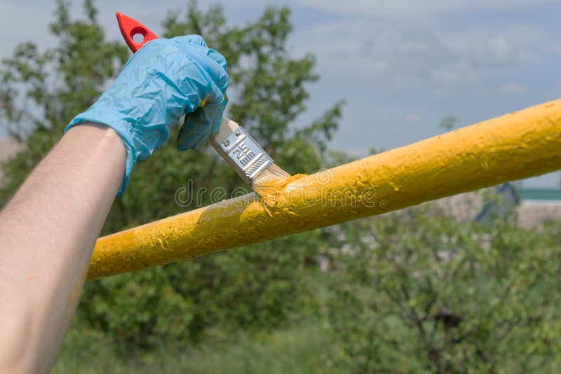 Gloved Hand Paints the Pipe in Yellow in the Garden Stock Image - Image ...