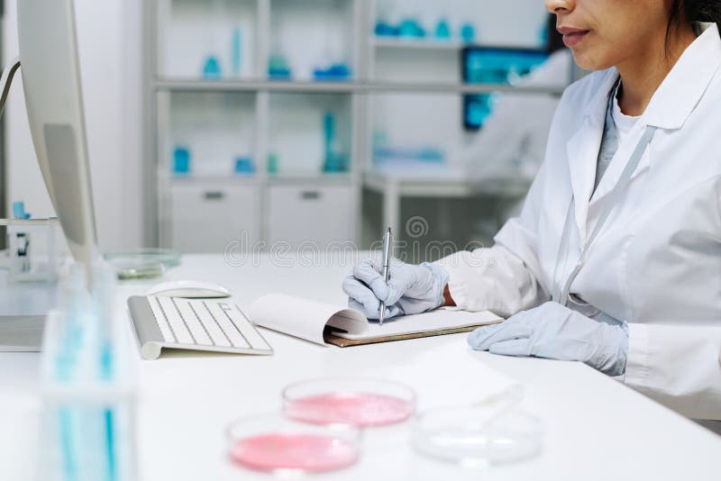 Gloved Hands of Young Female Scientist Making Notes in Clinical ...