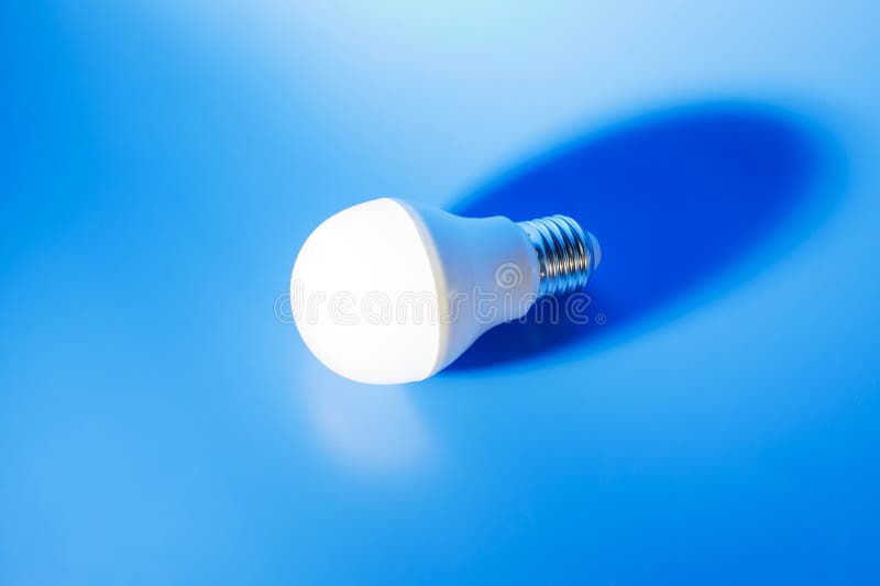 A Glowing Led Light Bulb Casts a Shadow on a Blue Background ...