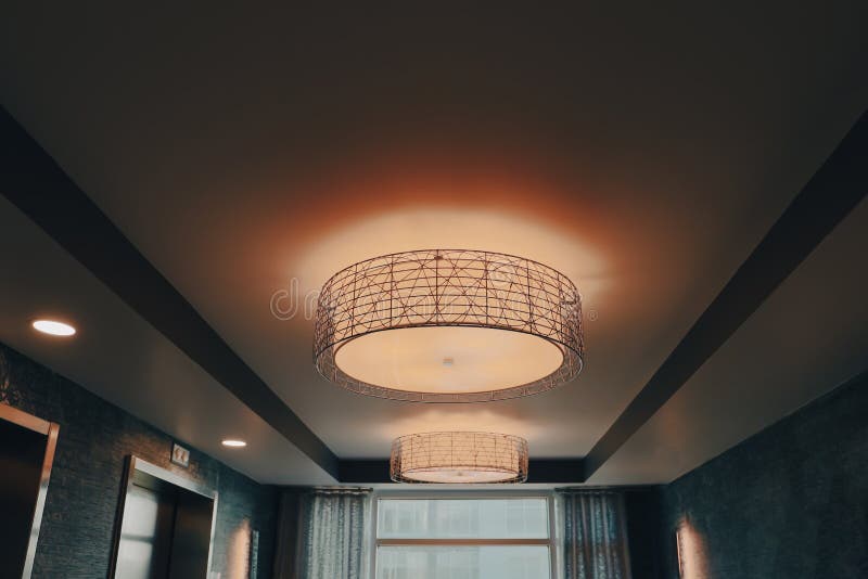 A Glowing and Lit Drum Light with Black Metal Accents on a Warm Ceiling ...
