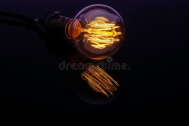 Glowing Retro Light Bulb with Reflection on Black Table Stock Photo ...