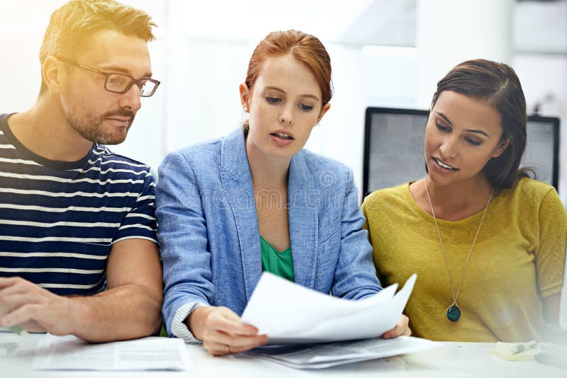 Going Over the Paperwork. Three Colleagues Looking Over Some Paperwork ...