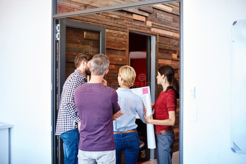 Going Over Their Plans. a Group of Colleagues Looking Over Some Plans ...