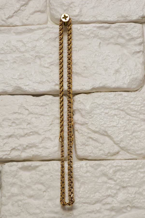 Gold Chain Hanging on a Light Color Decorative Brick Wall in the Center ...