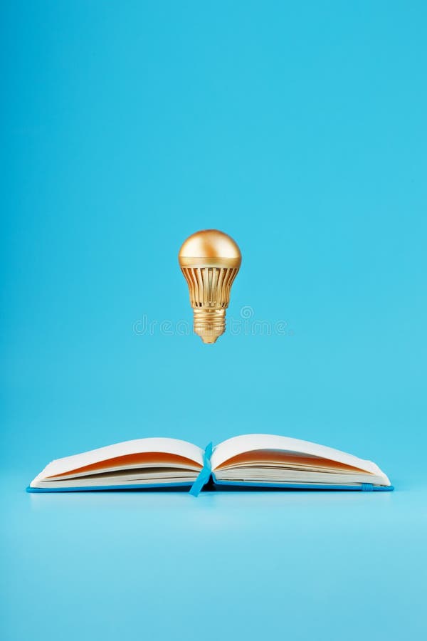 A Gold-colored Light Bulb Hangs Above the Blank Pages of a Notebook on ...