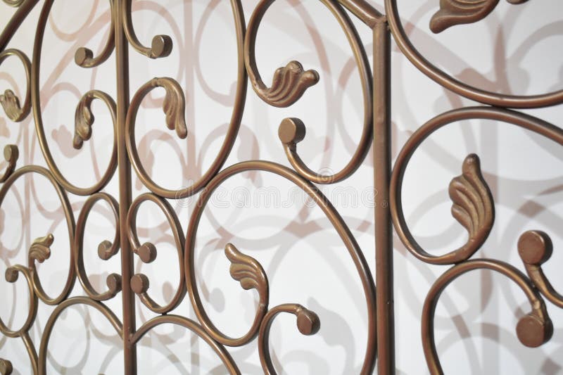 A Gold-Colored Metal Scroll Headboard with Shadows on the Wall Stock ...