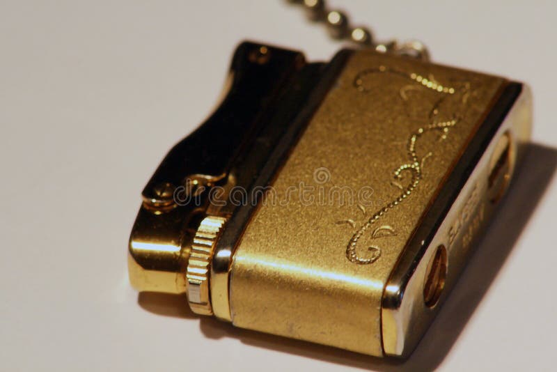 A Small Ladies Golden Gas Lighter with a Chain Hanging from it Stock ...