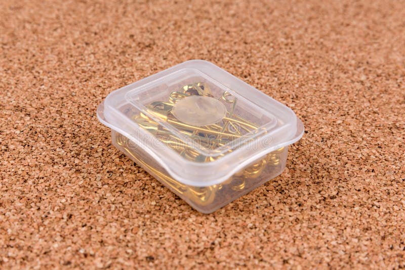 Gold Safety Pins in a Container on a Piece of Cork Stock Photo - Image ...