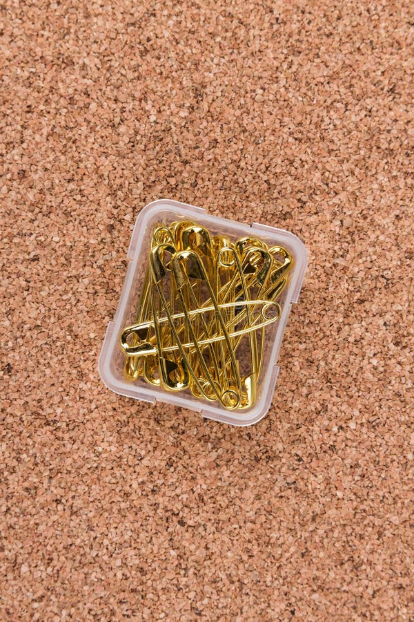 Gold Safety Pins in a Container on a Piece of Cork Stock Photo - Image ...