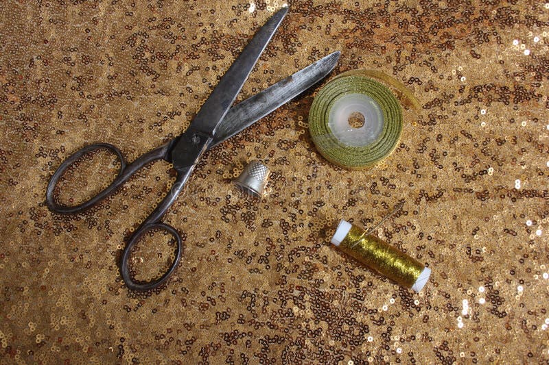 Gold Sequins on Fabric with Spool of Gold Metallic Thread and Thimble ...