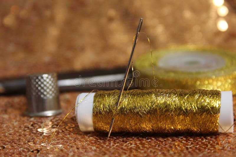 Gold Sequins on Fabric with Spool of Gold Metallic Thread and Thimble ...