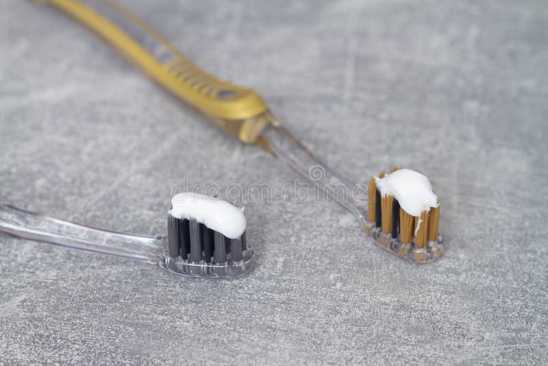 Gold and Silver Toothbrushes with Toothpaste on a Gray Background Stock ...