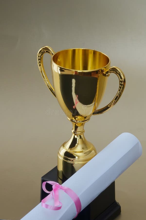 A Gold Trophy Cup with a Roll of Papers Near it Stock Photo - Image of ...