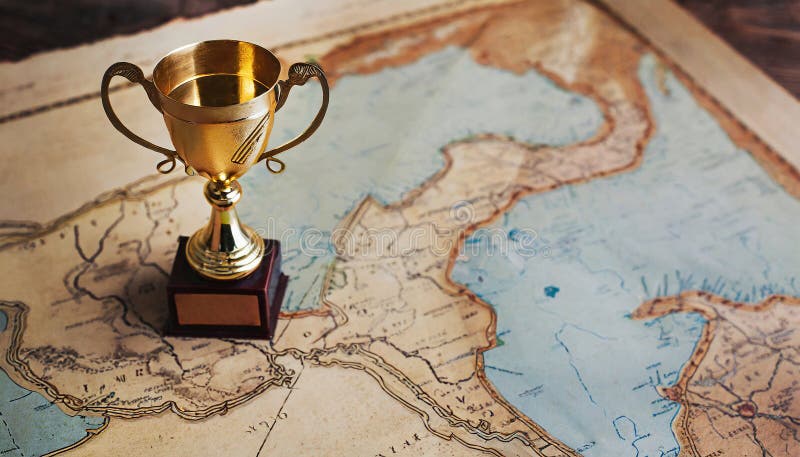 Gold Trophy Sits on Top of an Old Map with Mountains in the Background ...