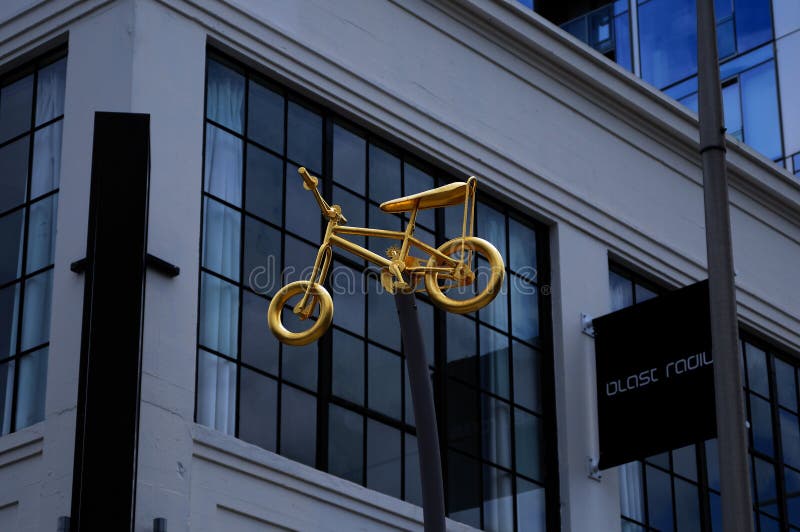 Golden Bicycle Statue on a Pole in Front of a Modern Building Editorial ...