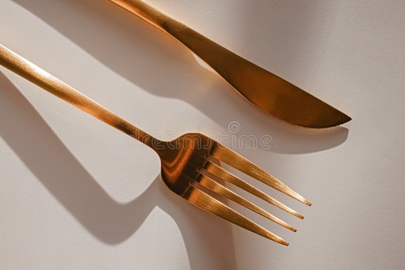 Golden Knife and Fork on the Table in Natural Light with Long Shadows ...