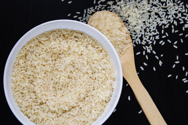 Golden Rice in a Bowl with Spoon on Dark Table Stock Photo - Image of ...