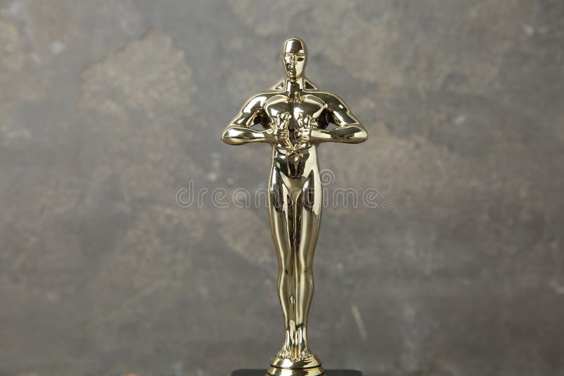 Golden Trophy in Shape of Human Figure Against Blurred Gray Background ...