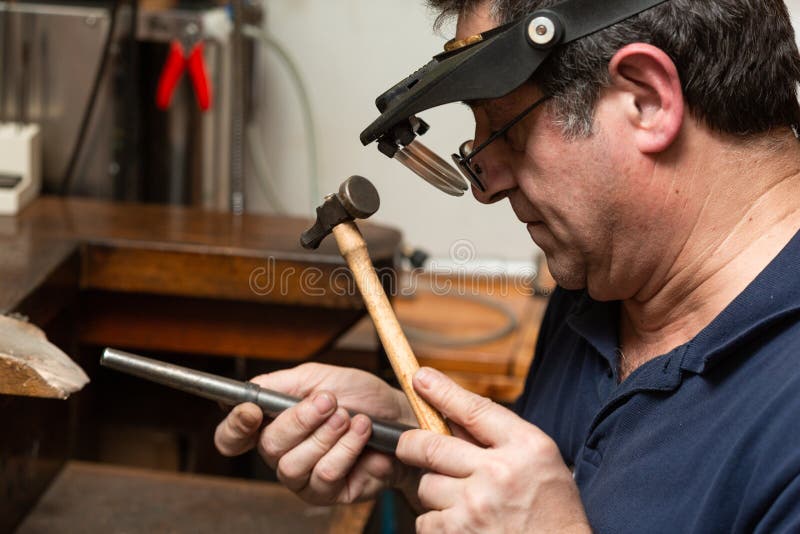 A Goldsmith Holds a Silver Ring and Shapes it with a Mold and a Hammer ...