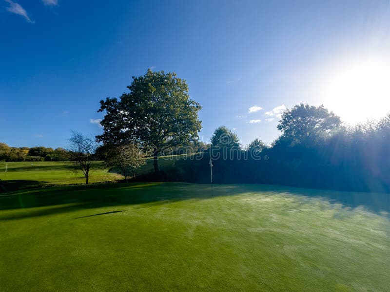 Golf Course Green with Blue Sky and Flag in View, Autumn Day with Dew ...