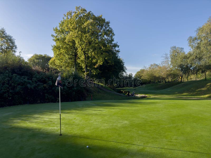 Golf Course Green with Blue Sky and Flag in View, Autumn Day with Dew ...