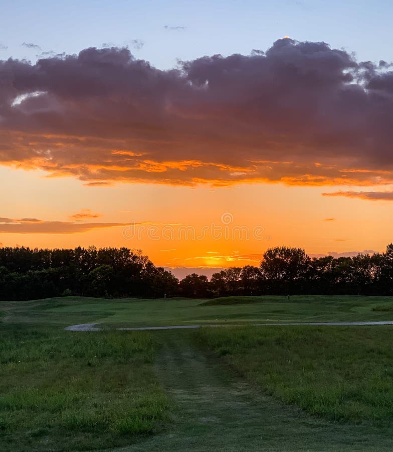 A Golf Course Sunset Over a Tree Line through the Fairway Stock Photo ...