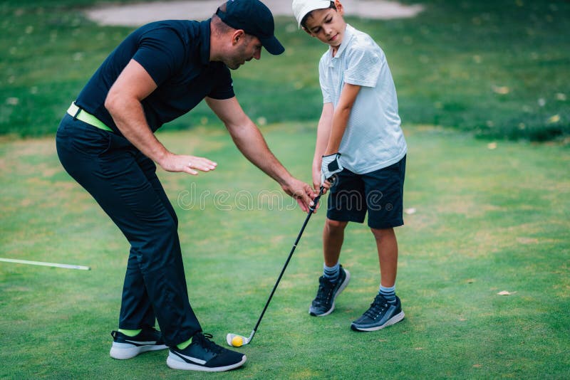 Personal Golf Lessons. Golf Instructor Adjusting Swing of a Young Boy ...