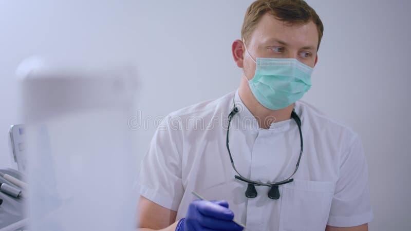 Good Looking Man Dentist with Protective Mask Explains To the Patient ...