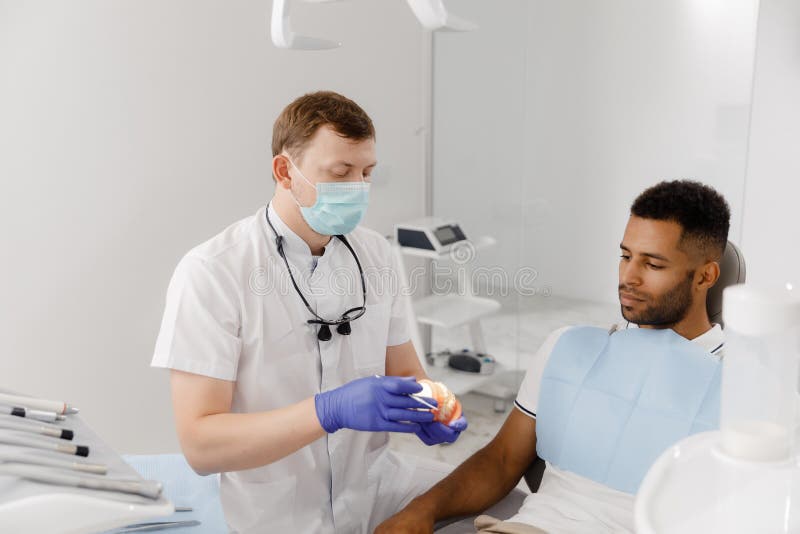 Good Looking Man Dentist with Protective Mask Explains To the Patient ...