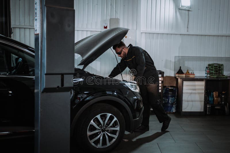 Good Looking Mechanic Guy Looking at the Car Engine in a Car Service ...