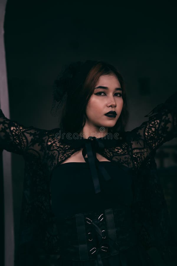 A Goth Asian Woman Dresses Up With Black Make Up And Wears Black