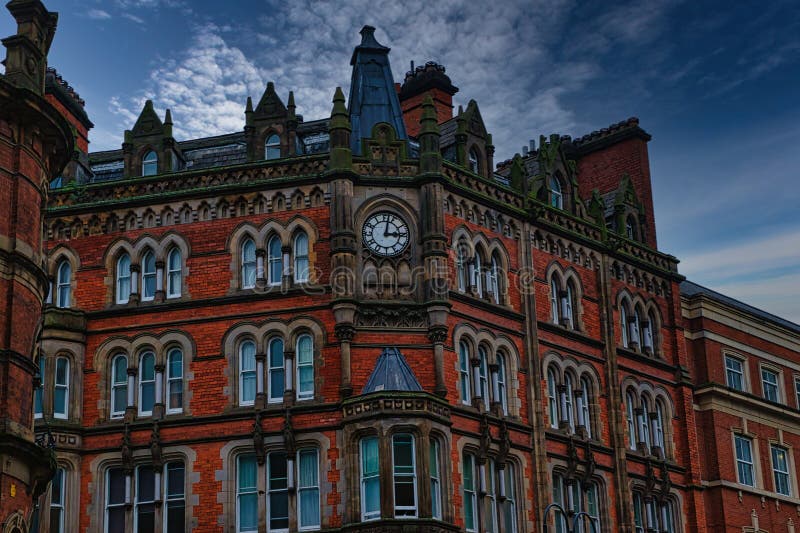 Gothic-style Red Brick Building with Clock Tower Under a Moody Sky in ...