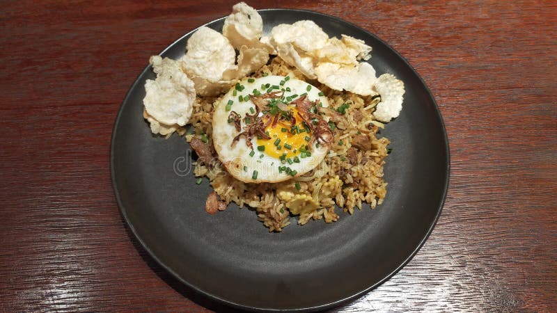 Gourmet Fried Rice with Sunny Side Up Egg and Crispy Toppings on Dark ...