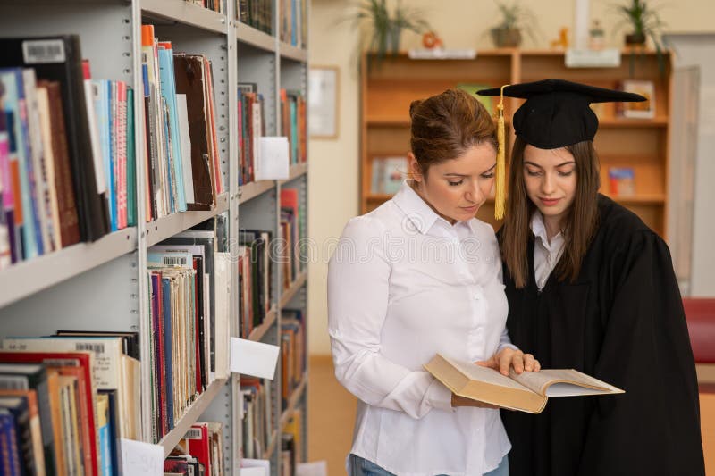 Graduate and Teacher Reading a Textbook in the Library. Stock Photo ...