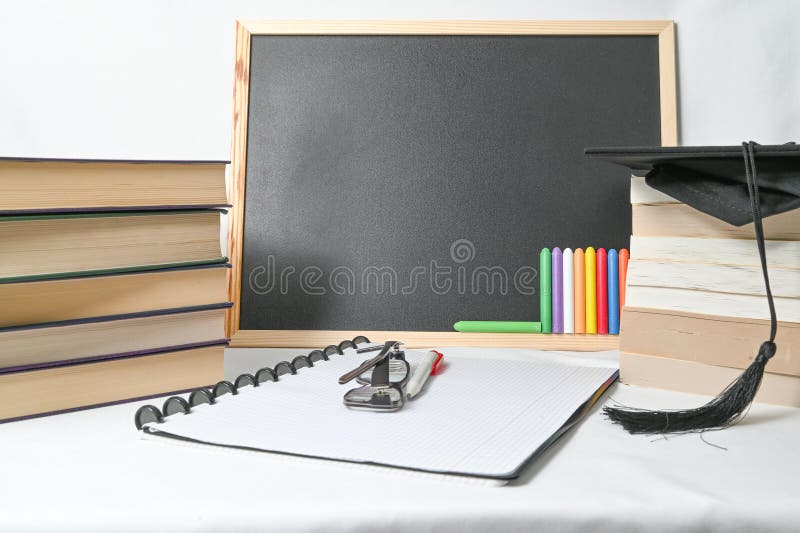 A Graduation Cap is Placed beside a Chalkboard Along with a Notebook ...