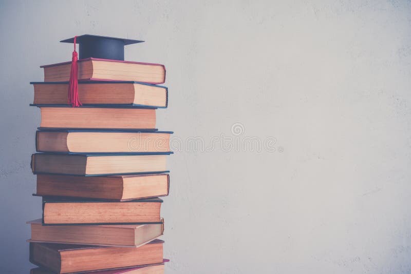 Graduation Cap on Stack of Many Antique Books on Shelf in Book Store or ...