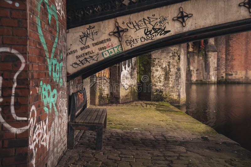 Graffiti-covered Bridge Situated Next To a River and Brick Wall ...