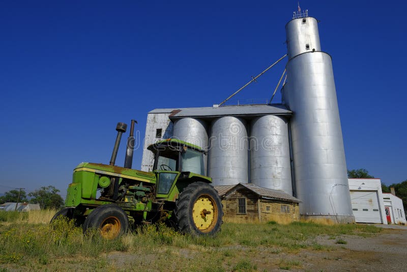 Grain Elevator Silo with Old Green Tractor Stock Photo - Image of ...