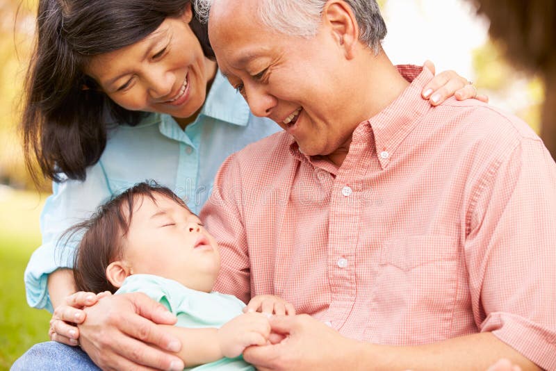 Grandparents Holding Sleeping Grandson in Park Stock Photo - Image of ...