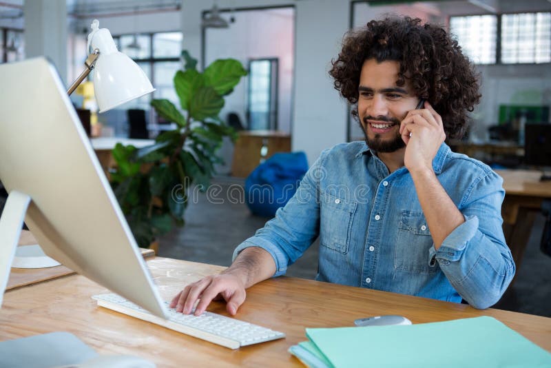 Graphic Designer Using Computer while Talking on Mobile Phone Stock ...