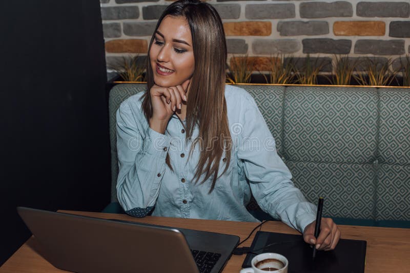 Graphic Designer Working on Laptop while Using Graphic Tablet in Cafe ...