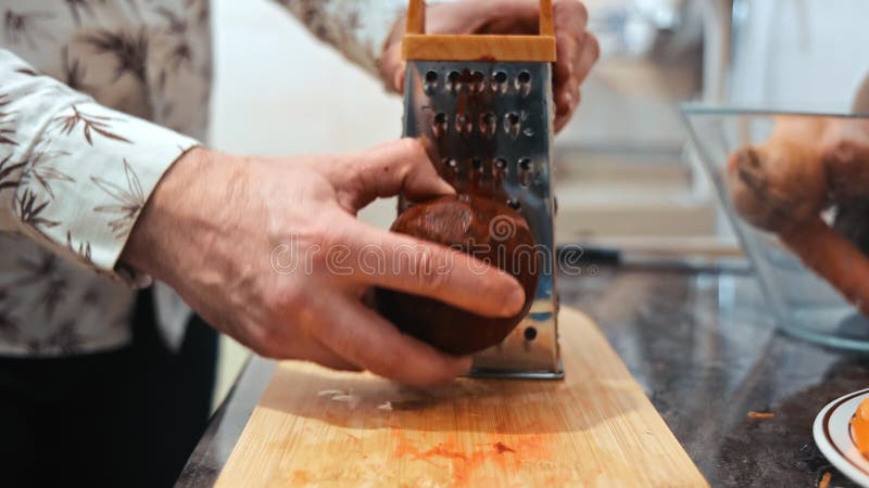 Grating a Beetroot in the Kitchen, a Person Grates a Beetroot on a ...