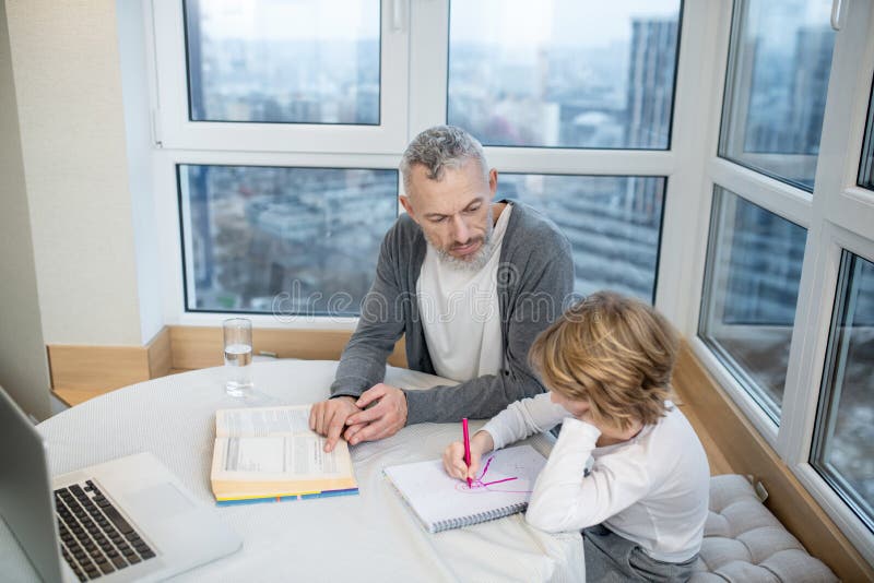 Gray-haired Bearded Man Sitting with His Son at the Table while he ...