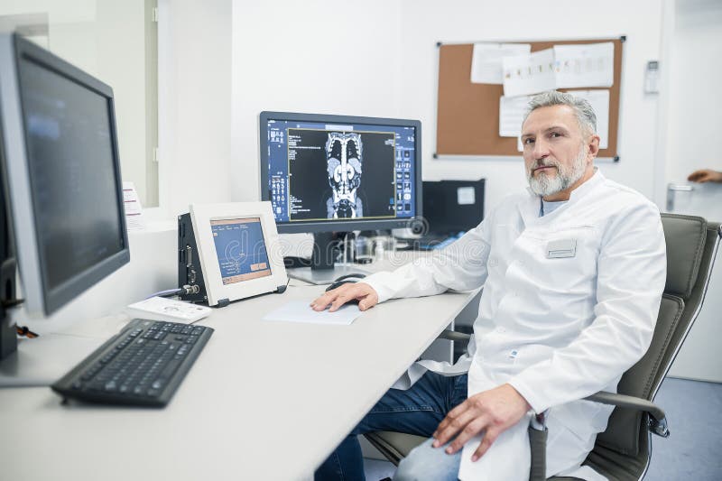 Gray-haired Doctor in a Lab Coat Sitting at His Working Place Stock ...