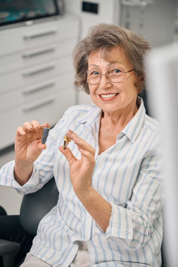 Gray-haired Lady Holds Model of Dental Implant Components Stock Photo ...