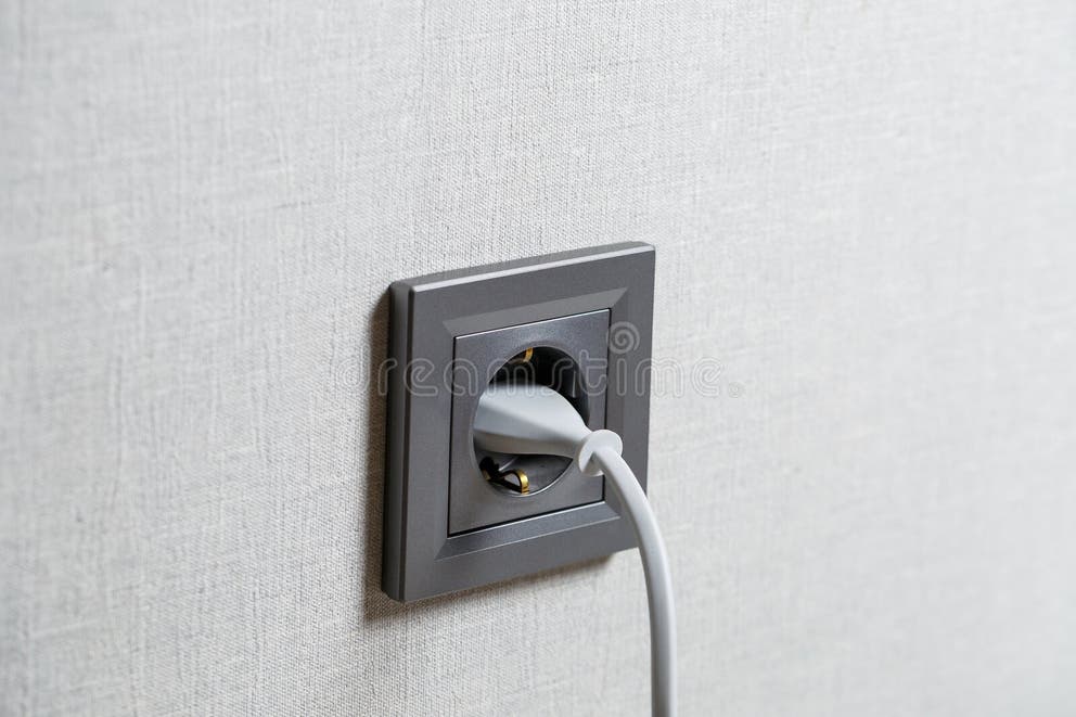 A Gray Outlet on the Wall Which Includes a Device with a White Cord ...