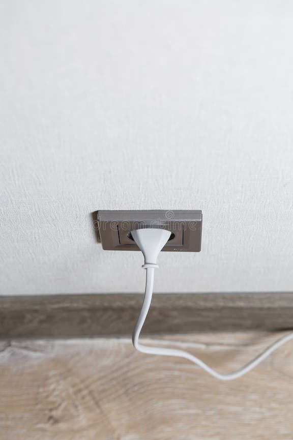 A Gray Outlet on the Wall Which Includes a Device with a White Cord ...